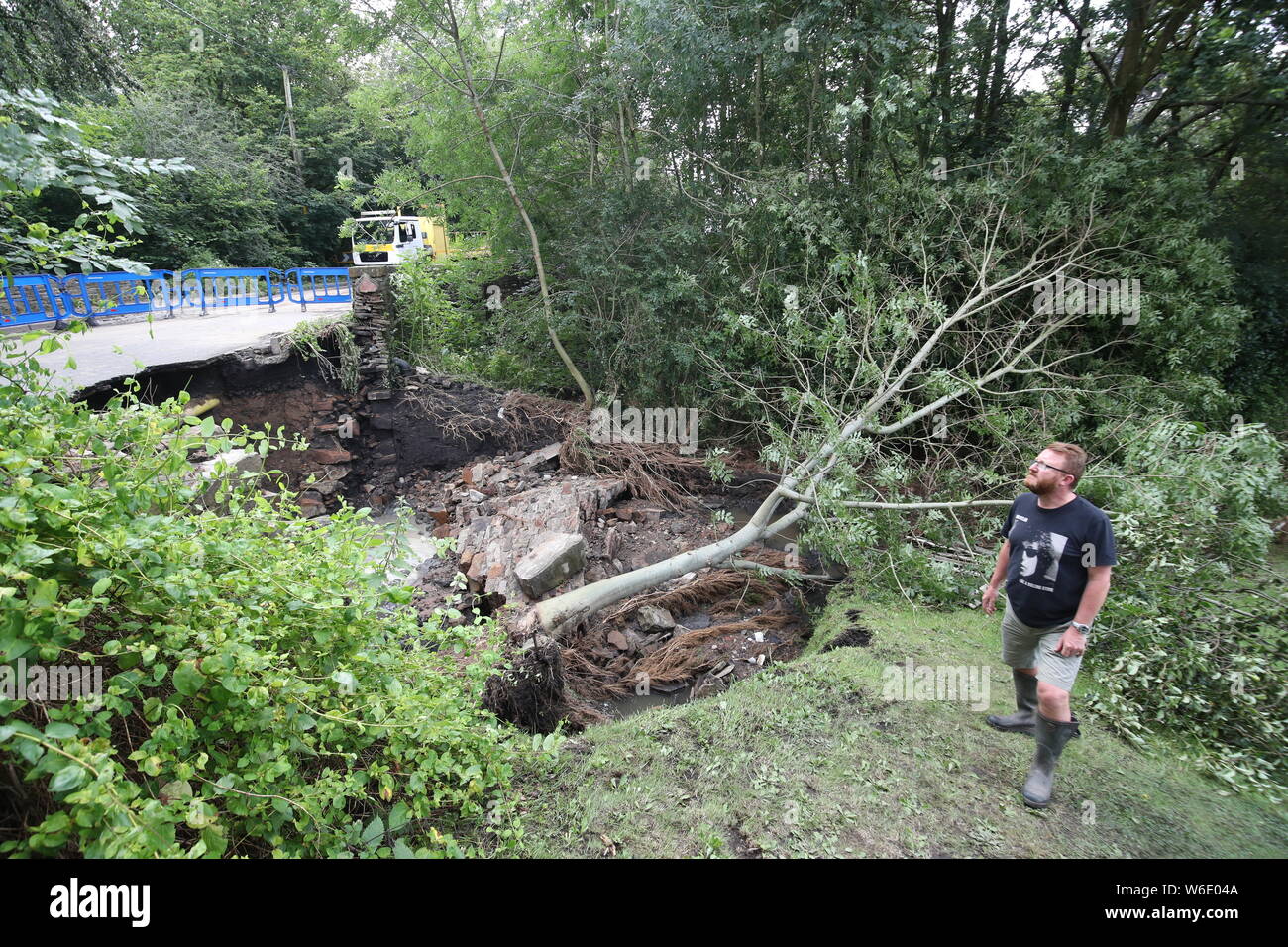 Workers look at a partially collapsed bridge in Poynton, Cheshire ...