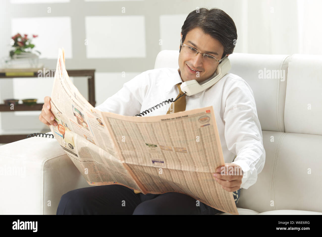 Businessman talking on a landline phone and reading a newspaper Stock ...