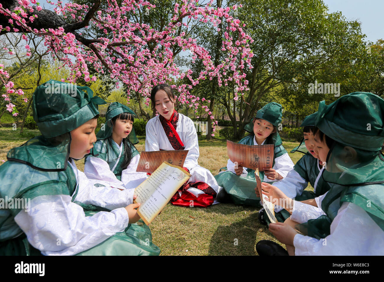 Chinese students dressed in traditional costumes read Chinese classics ...