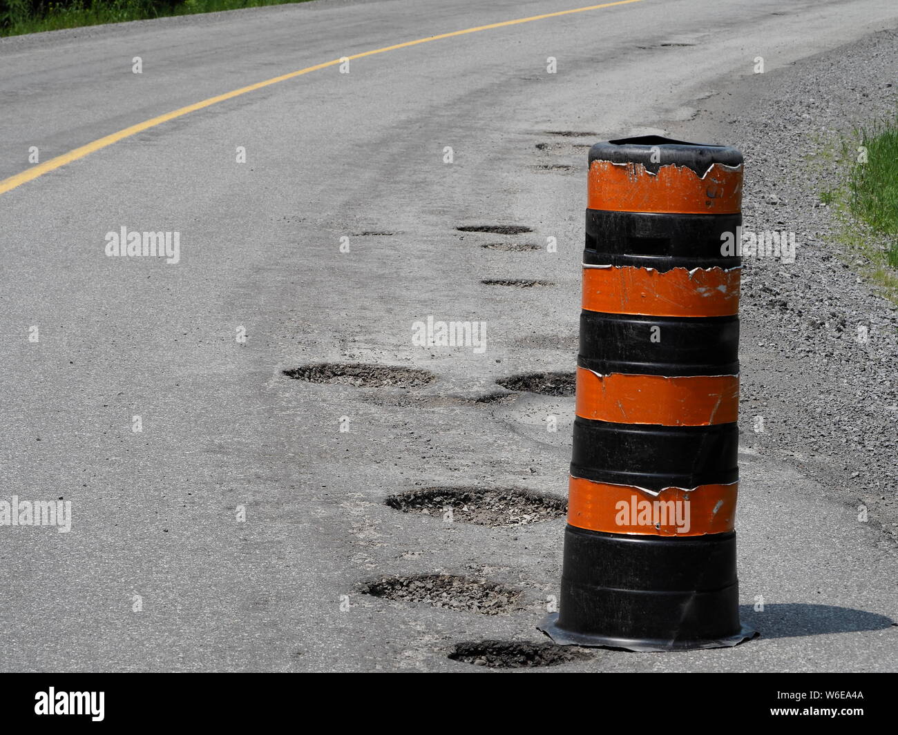 An orange and black traffic cone marking a series of deep potholes ...