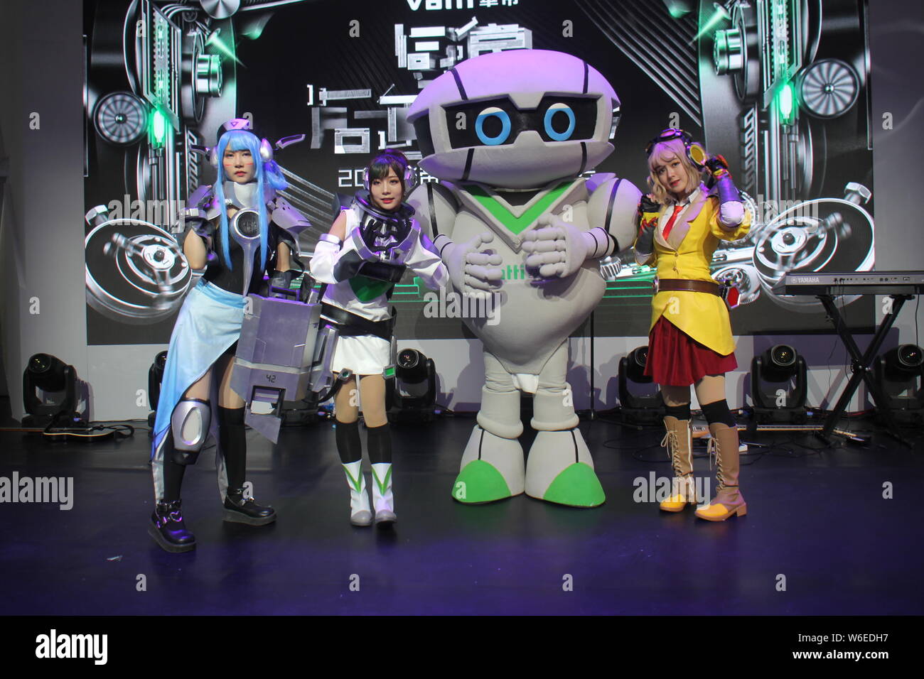 Female cosplayers take photos with an AI robot during the Appliance & Electronics World Expo ...