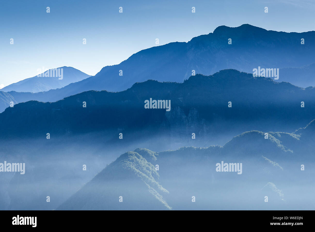 Hazy blue mountain range covered by fog in winter Stock Photo - Alamy