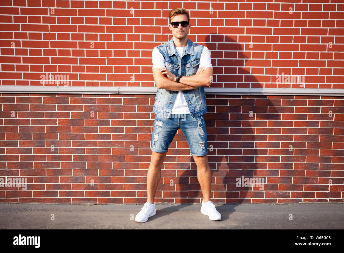 casual young man stands with his back against a brick wall Stock Photo ...