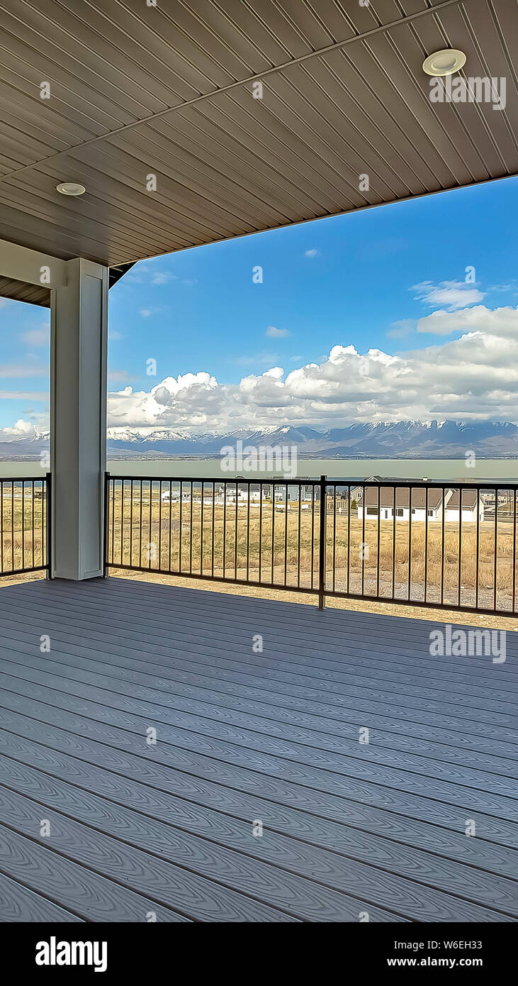 Vertical frame Balcony with view of cloudy blue sky over homes lake and ...