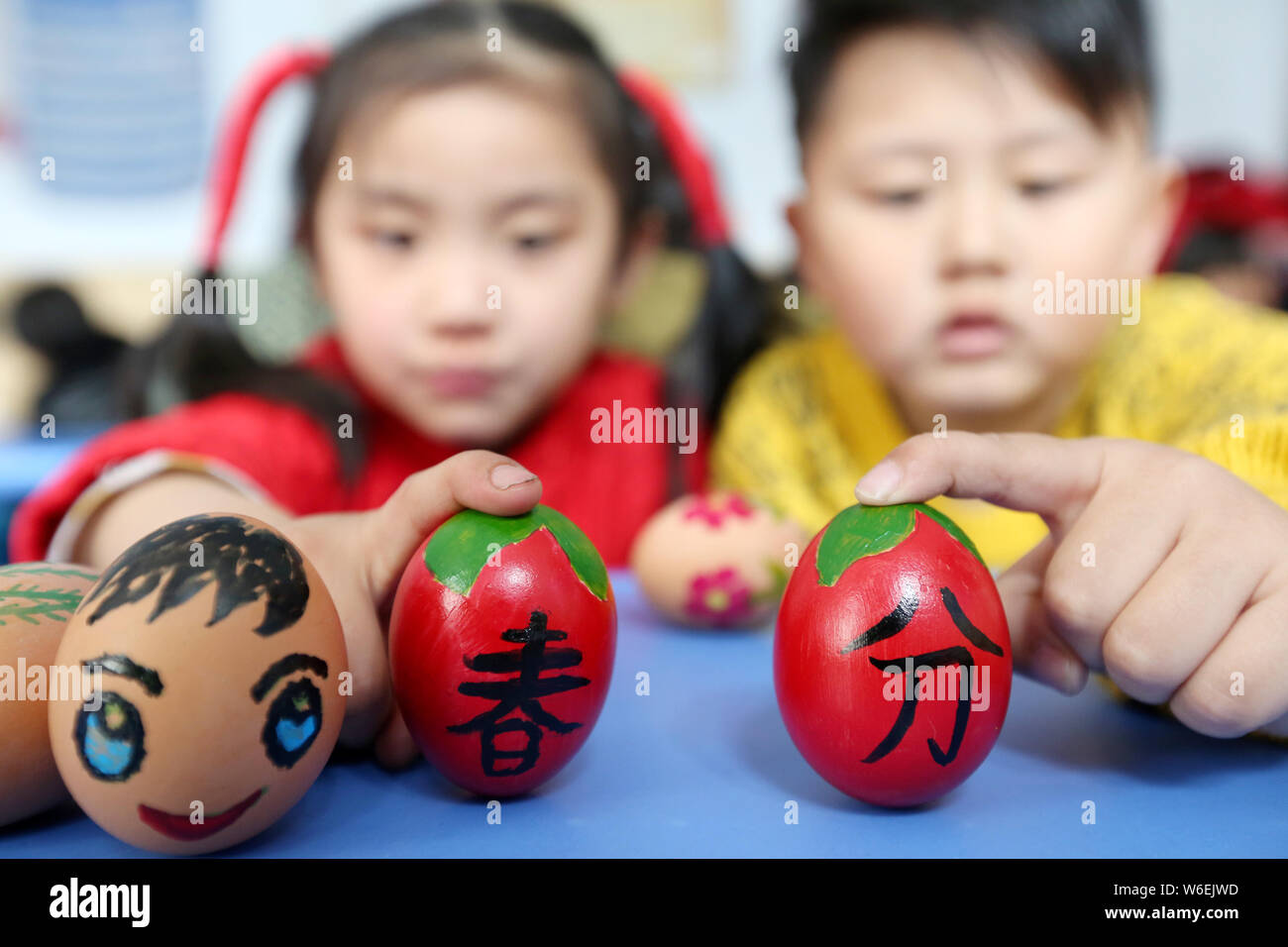 Children show eggs painted with Chinese characters and colors to mark ...