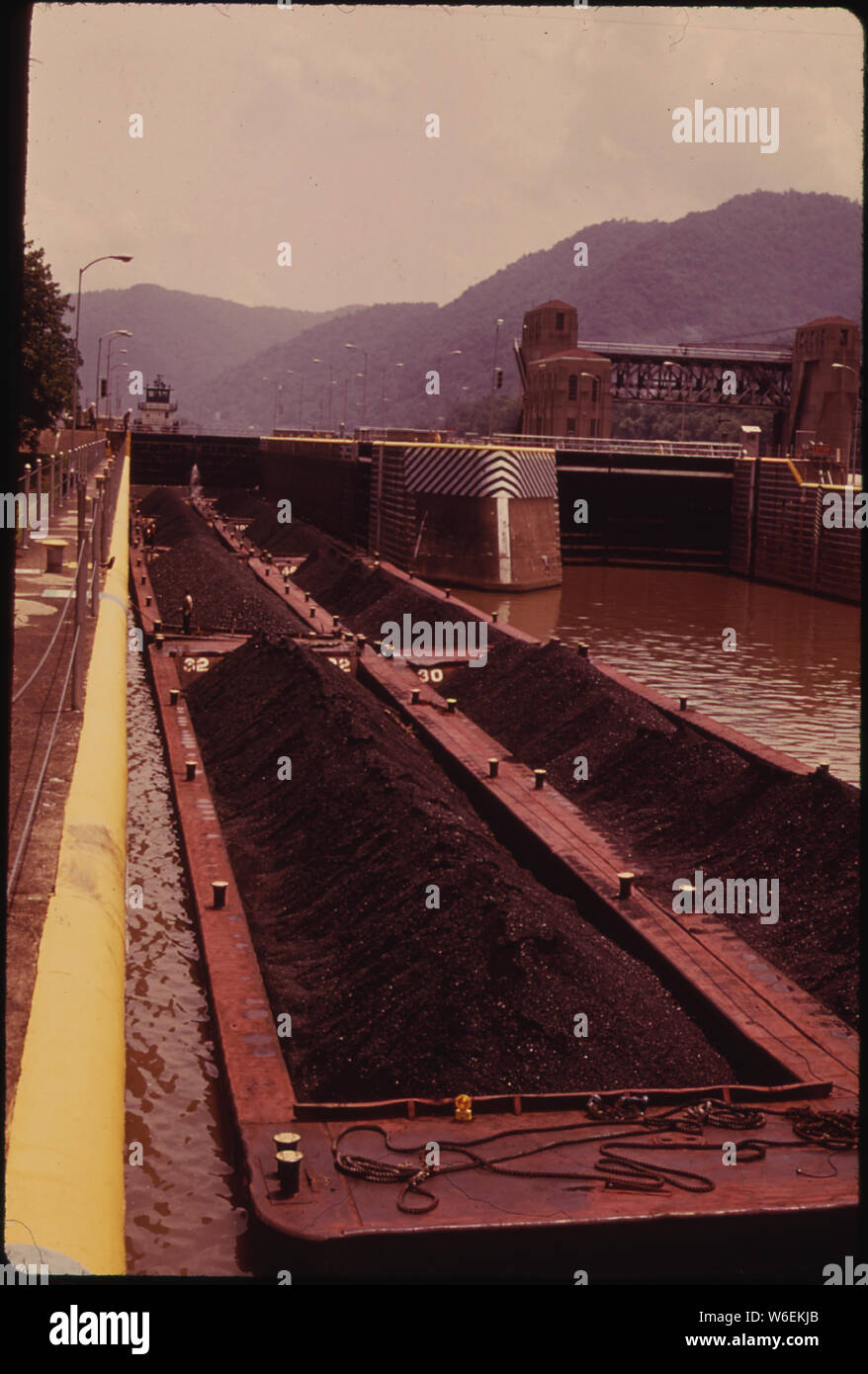 A COALBURG TUG AND EIGHT COAL BARGES GO DOWNSTREAM THROUGH THE LONDON ...