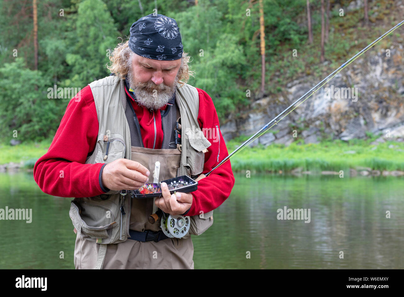 an elderly fisherman with a fishing rod or a spinning rod and with a ...