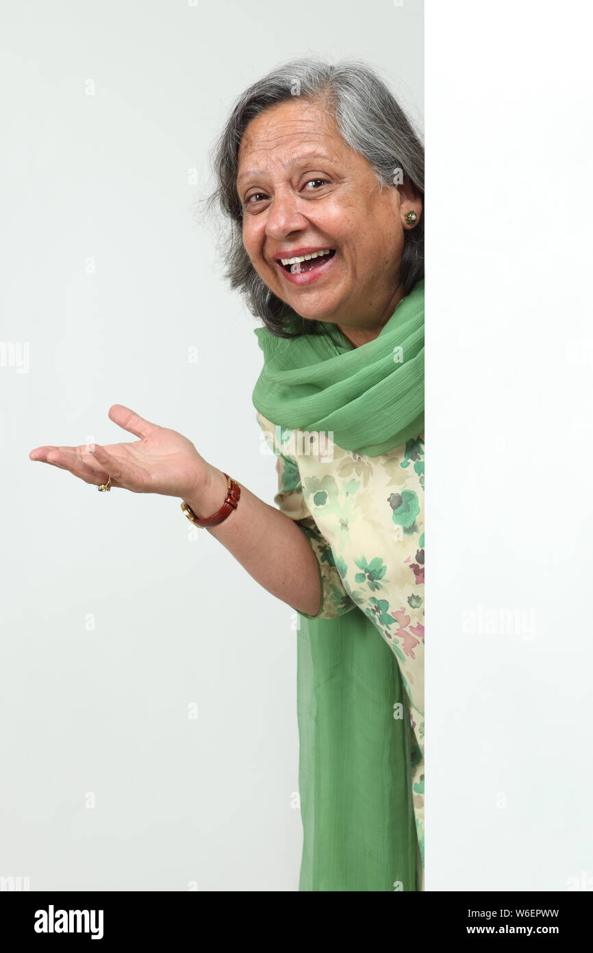 Old woman hiding behind a placard and smiling Stock Photo - Alamy