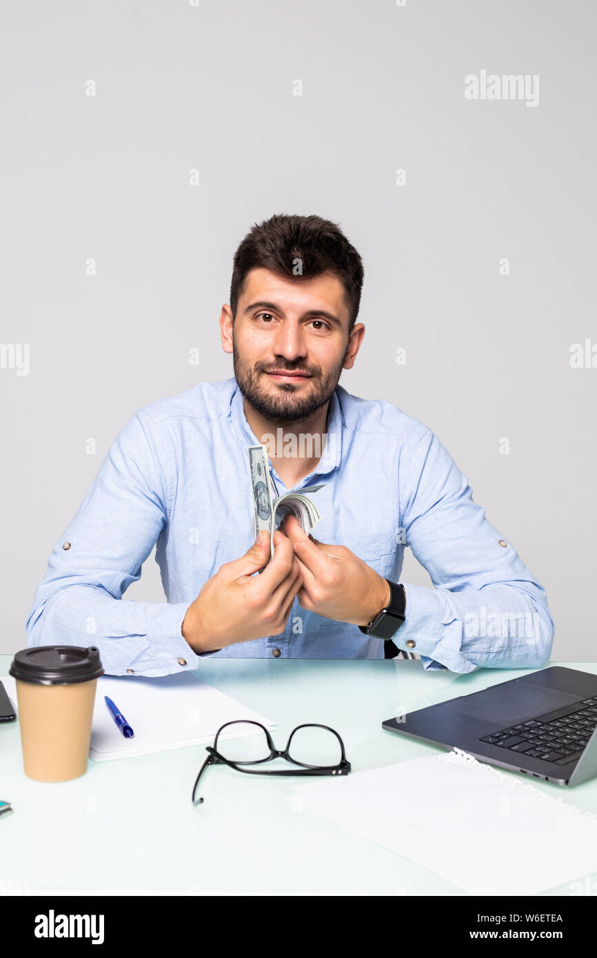 Young man holding dollars money sitting at his office desk Stock Photo ...