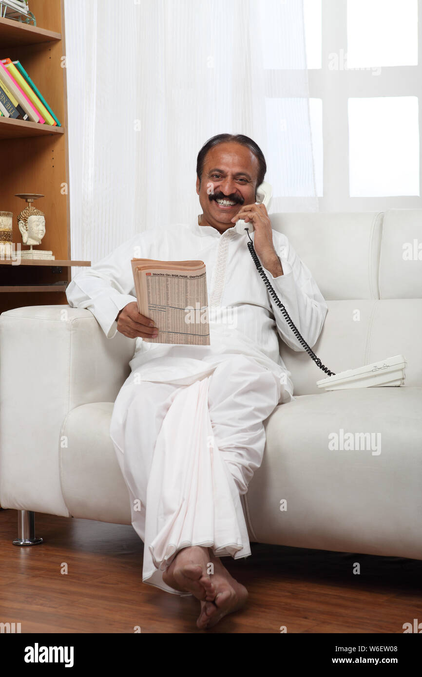 Bengali man talking on landline phone and holding newspaper Stock Photo ...