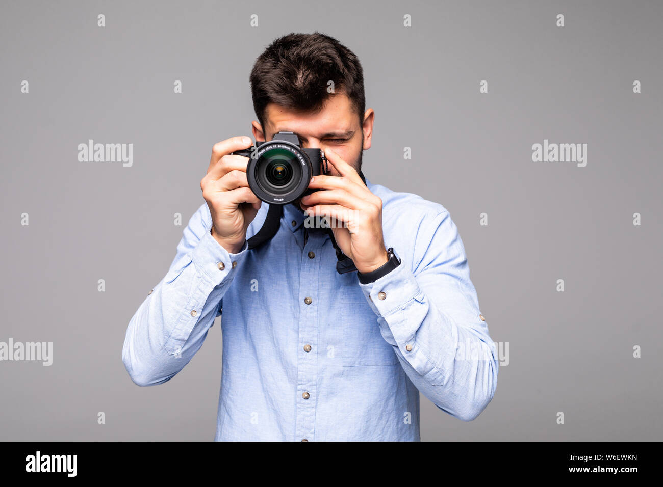 Young man take photo with dslr camera looking at camera over gray ...