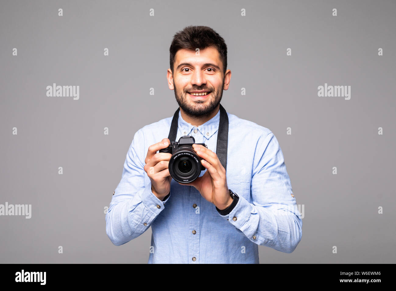 Young man take photo with dslr camera looking at camera over gray ...