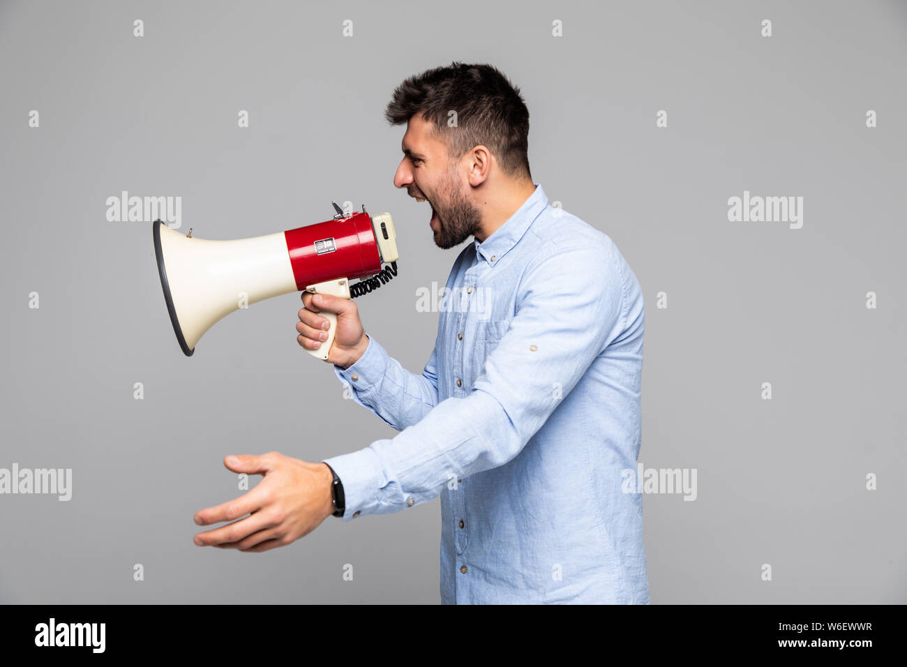 Side view of angry man shouting through megaphone against white ...