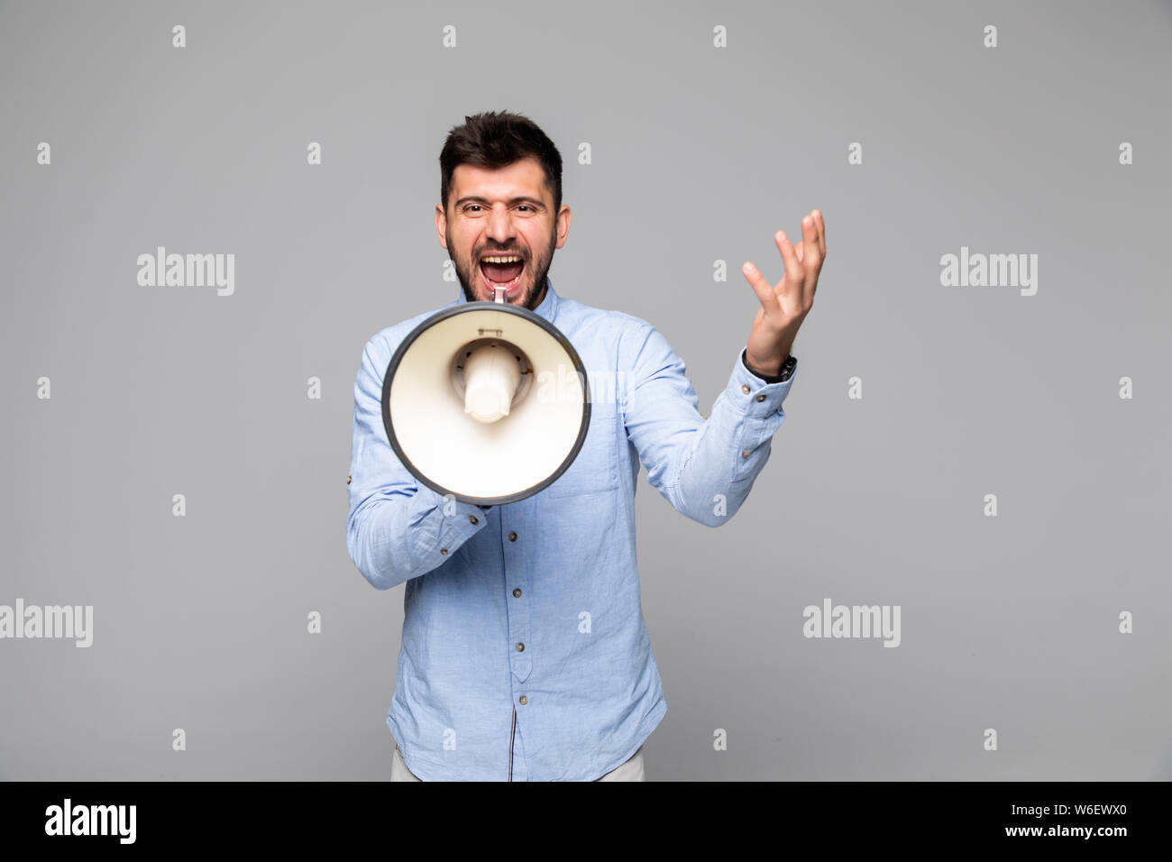 Side view of angry man shouting through megaphone against white ...