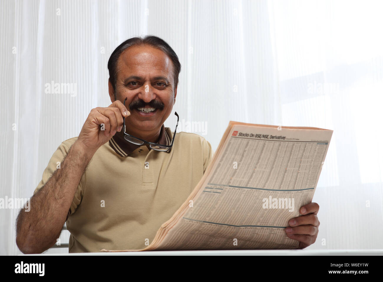Old man holding a newspaper and smiling Stock Photo - Alamy