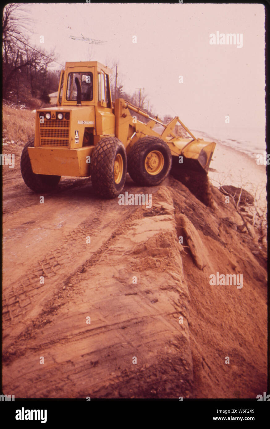 ARMY EARTHMOVER PILES LOOSE DIRT TO REINFORCE LAKE-ERODED LAKE SHORE ...