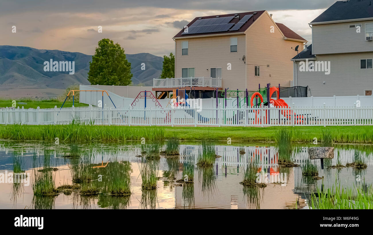 Panorama Shiny grassy pond with reflection of the playground homes ...