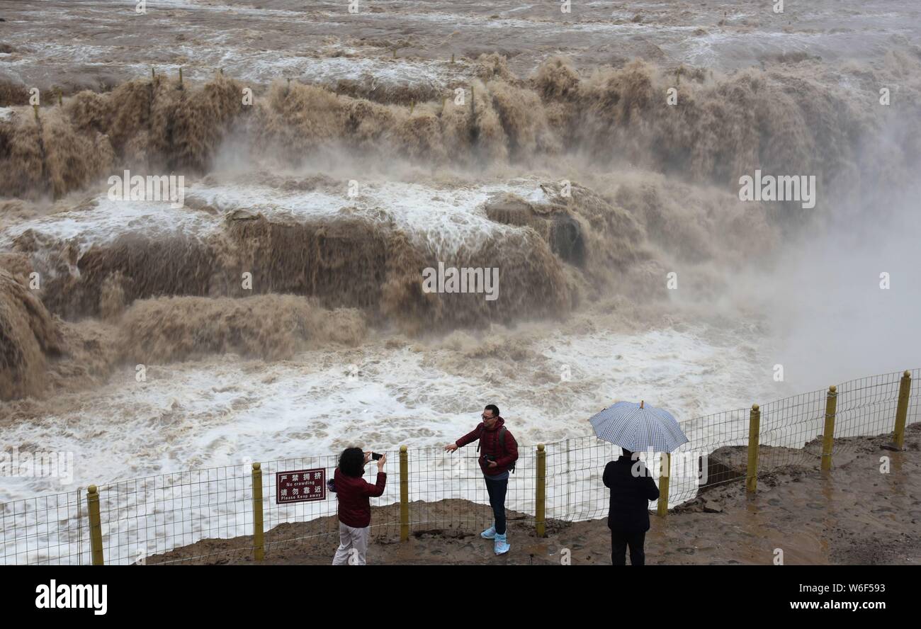 Tourists visit the Hukou Waterfall scenic spot along the Yellow River ...