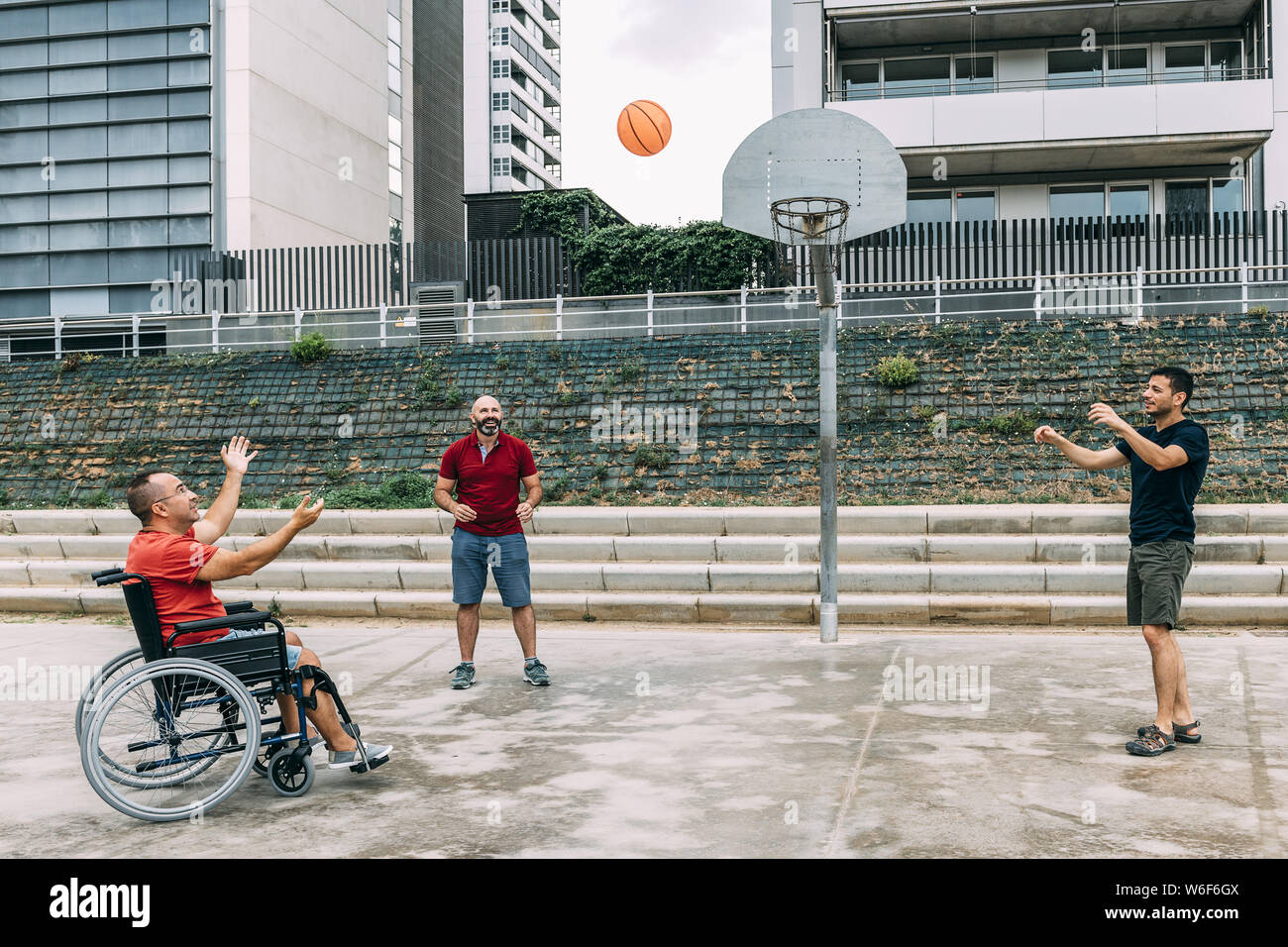joyful disabled man in wheelchair playing basketball with friends with ...