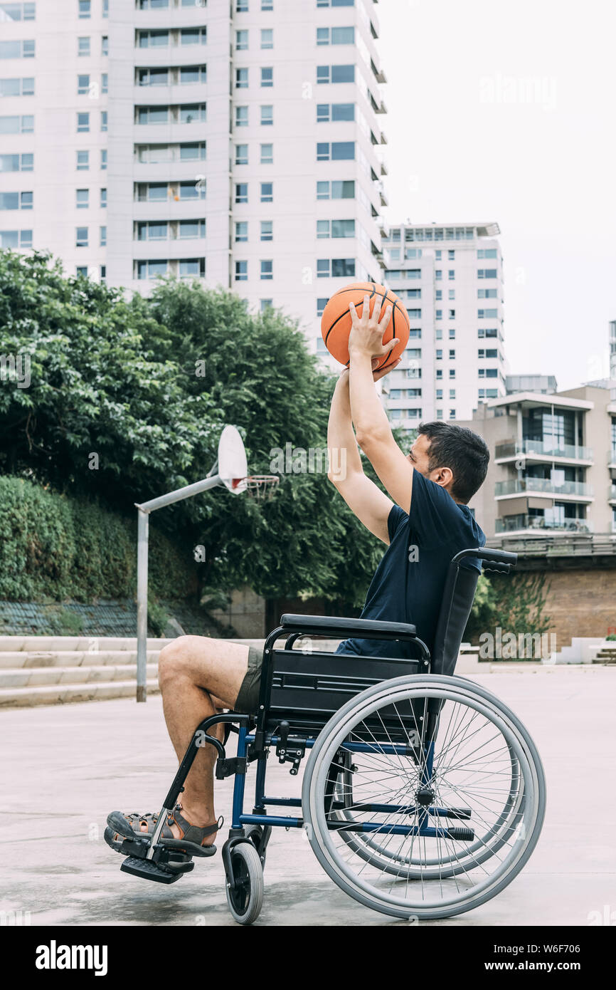 disabled man in wheelchair throwing ball to basket alone, concept of ...