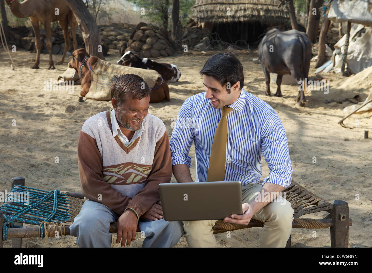 Executive explaining to a farmer with a laptop Stock Photo - Alamy