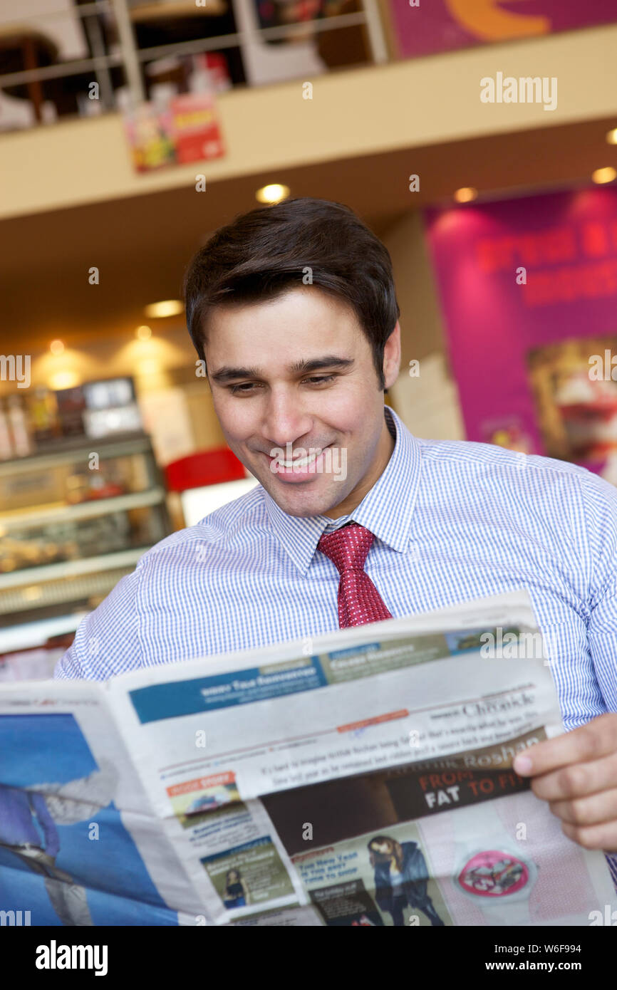 Businessman reading a newspaper in a cafeteria Stock Photo - Alamy