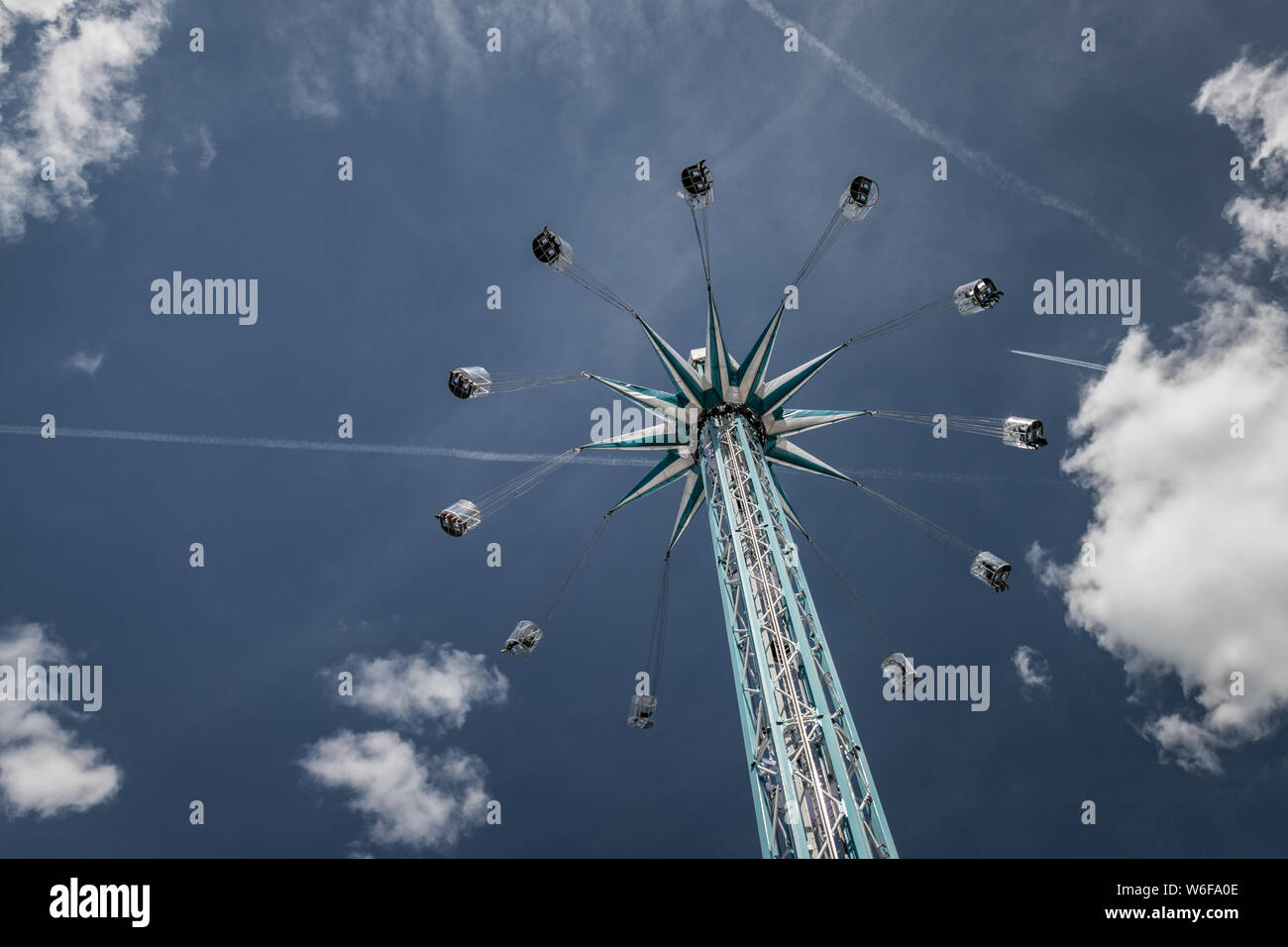 Amusement ride at chairoplane with flying people in front of a blue and ...