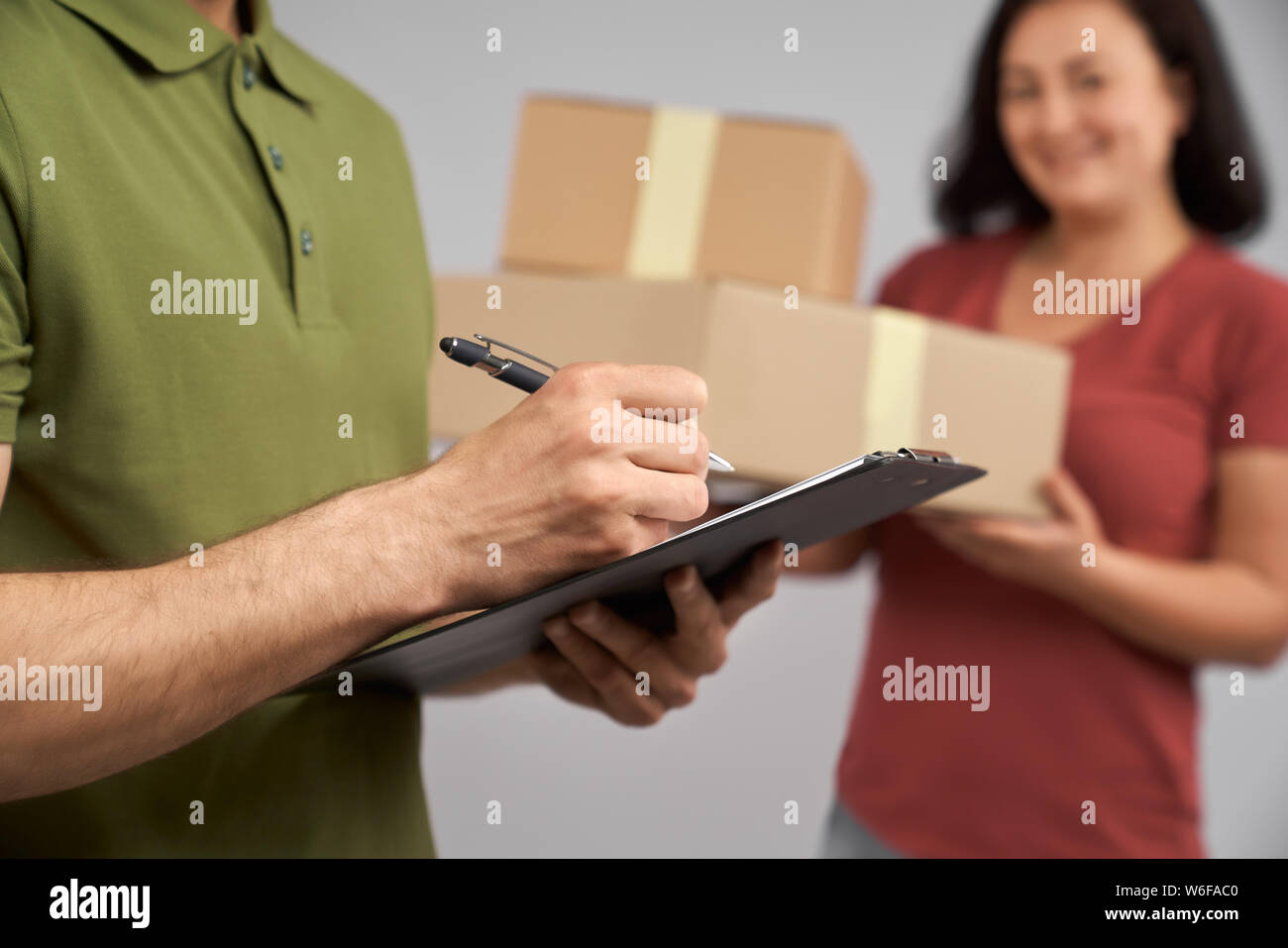 Close up of delivery man in green t shirt holding folder with documents ...