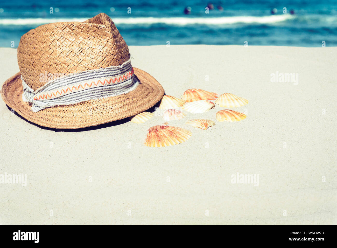 Vintage summer wicker straw beach hat on the sand with seashells ...