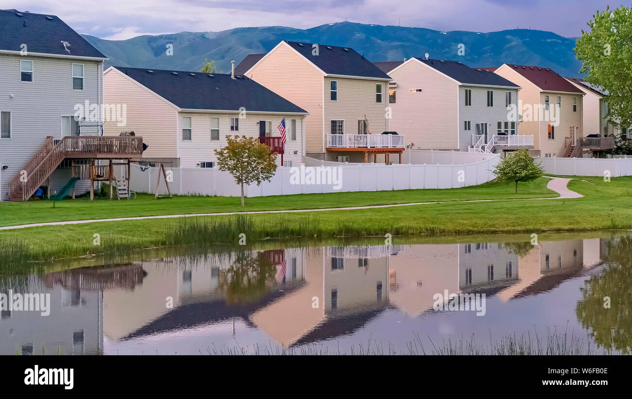 Panorama Shiny pond and pathway amid a grassy terrain in front of homes ...