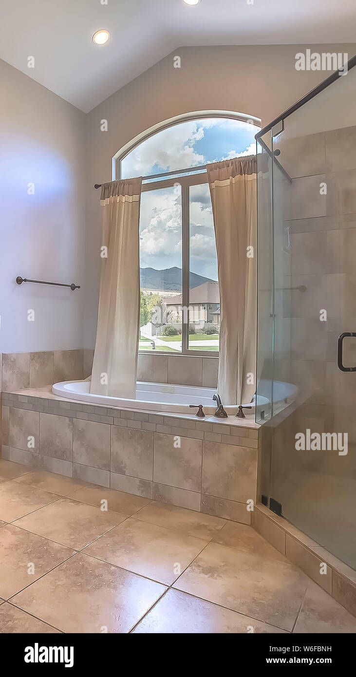 Vertical frame Oval bathtub in front of the arched window of a bathroom ...