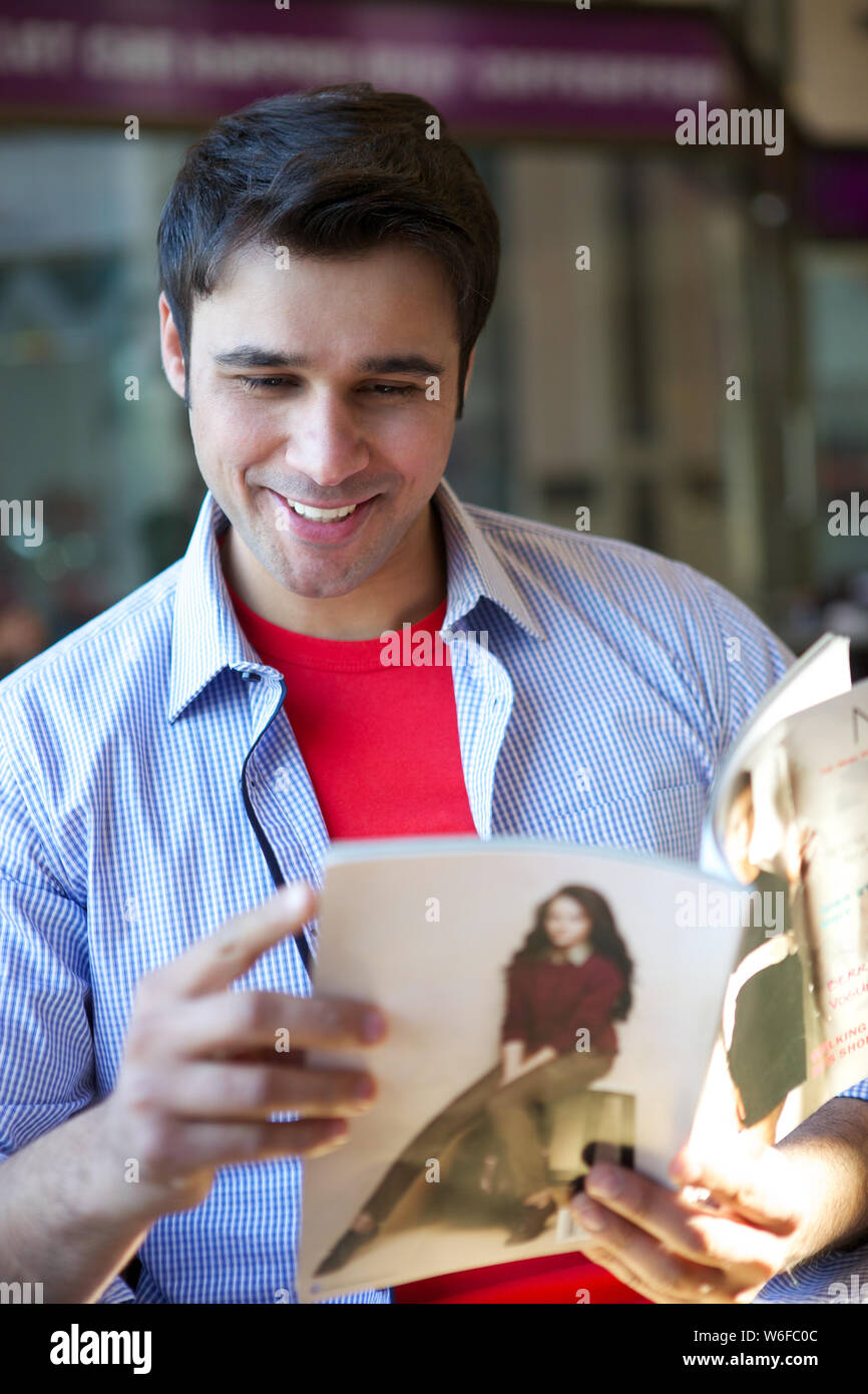 Man reading magazine in a cafeteria Stock Photo - Alamy
