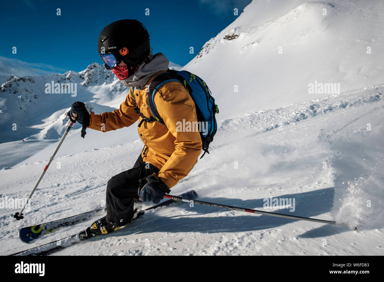 A teenage male skier, skiing fast and wearing a bandana against the ...