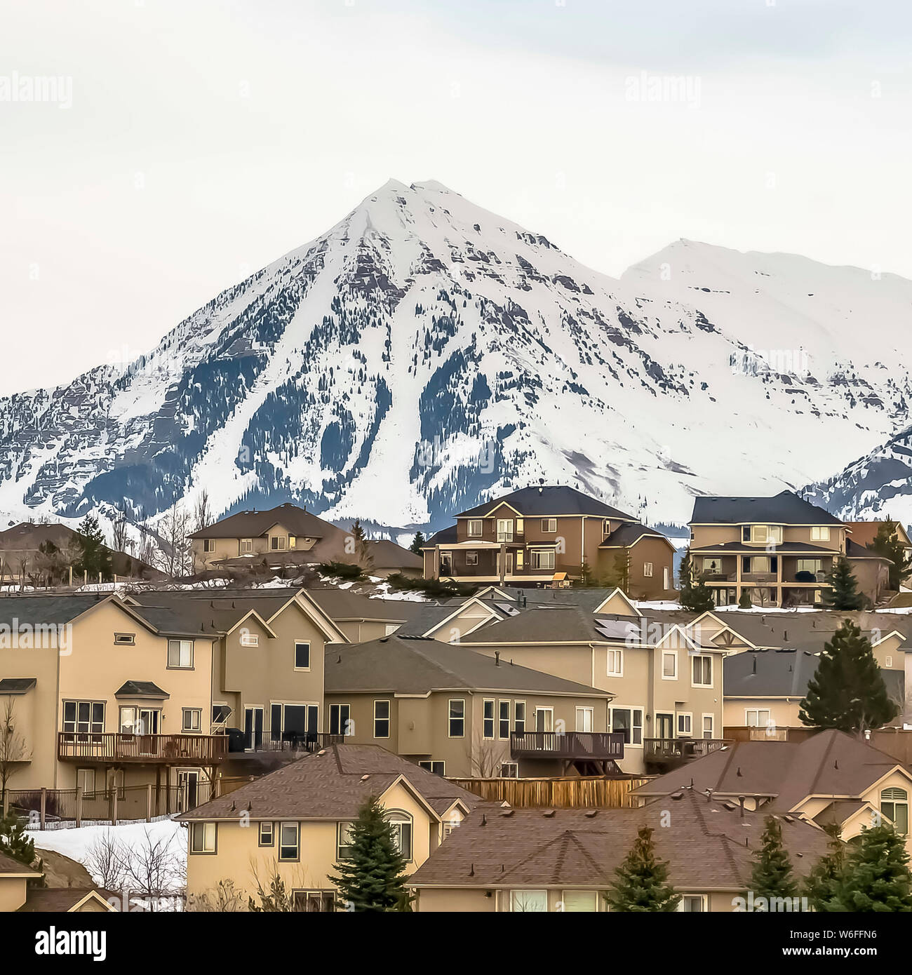 Square frame Hill homes with rugged snow covered mountain peak in the ...