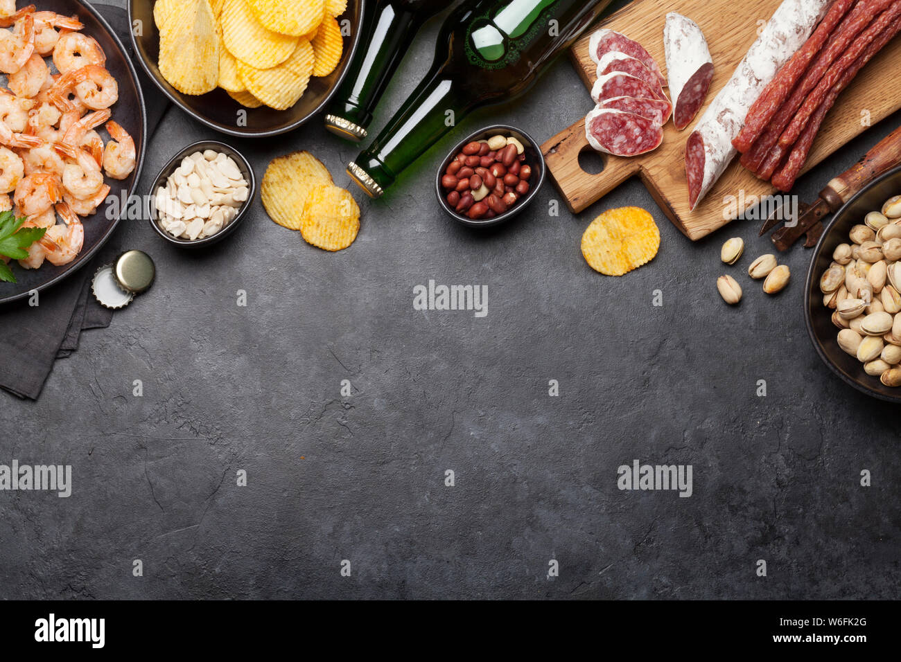Draft beer and snacks on stone background. Nuts, chips, sausages and ...