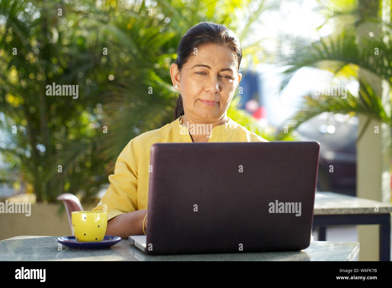 Old woman working on a laptop in a cafeteria Stock Photo - Alamy