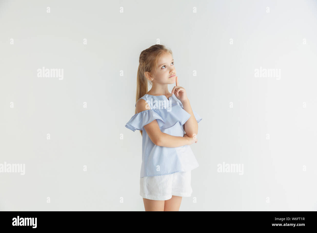 Stylish little smiling girl posing in casual clothes isolated on white ...