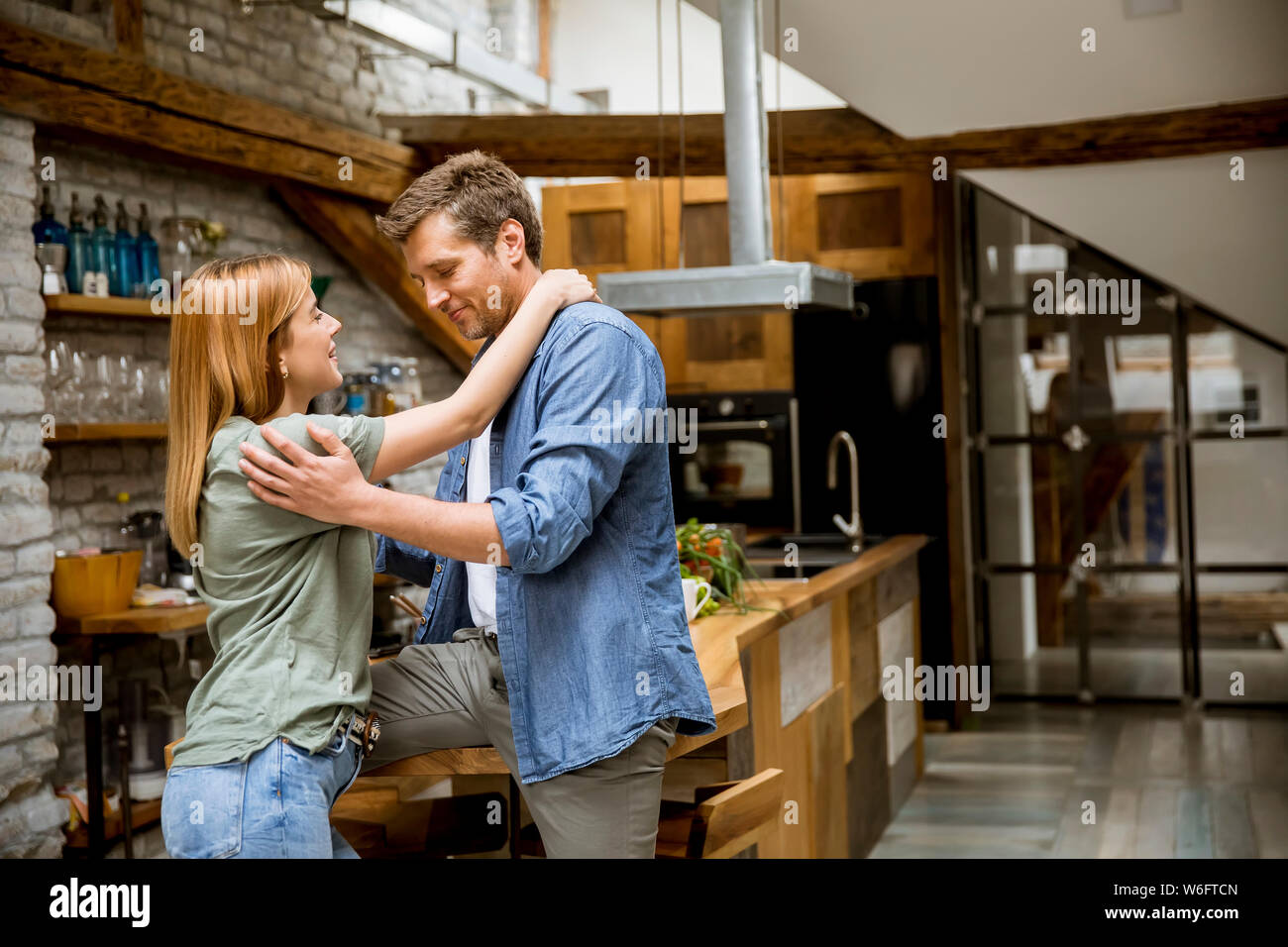 Cute young couple hugging while cooking in their apartment kitchen ...