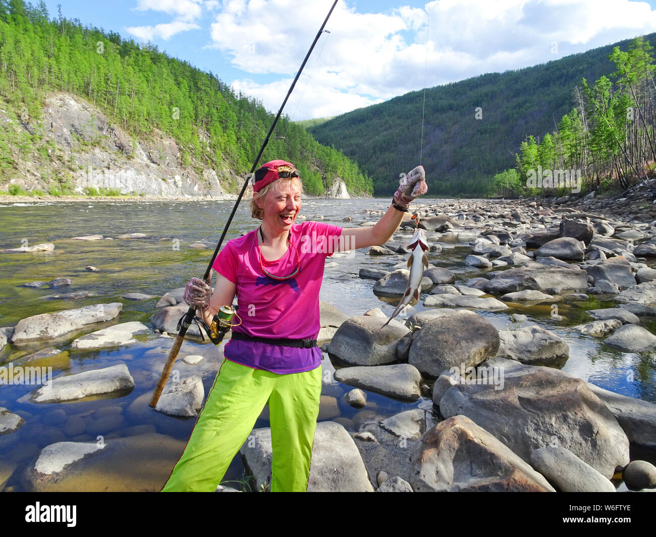 Happy young fisherwoman caught a big fish - lenok. Trophy catch. Good ...