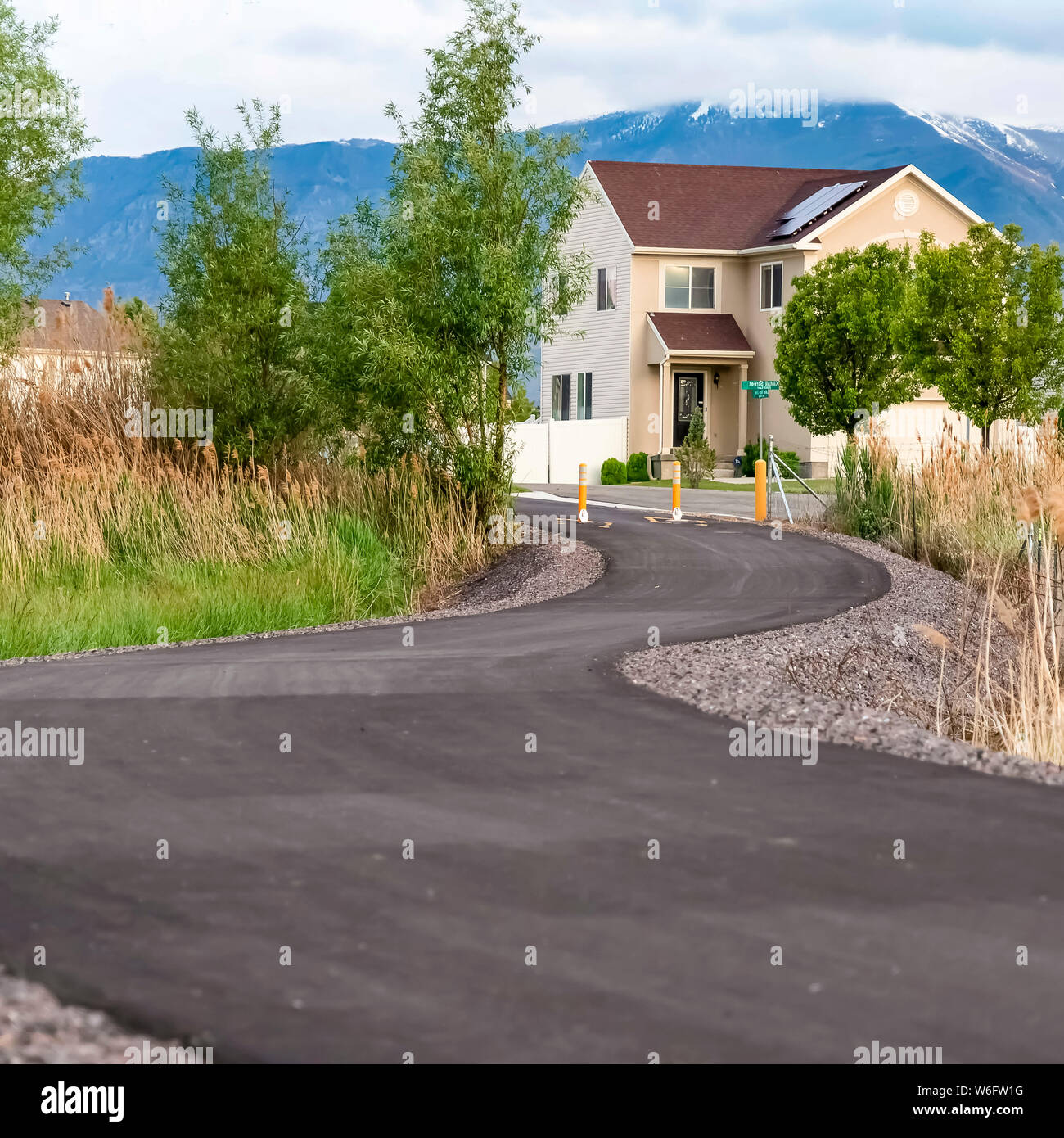Square Winding road leading to distant homes with mountain and cloudy ...