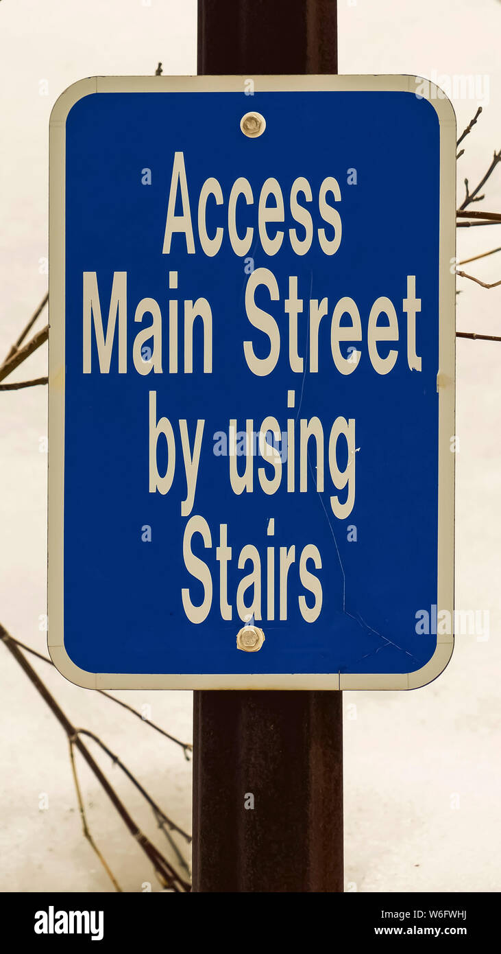Vertical Close up of a blue sign that reads Access Main Street By Using ...