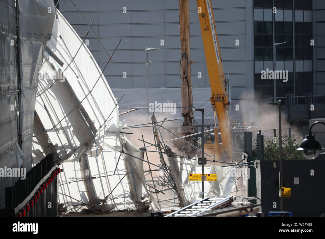 A mechanical digger begins to clear the area of the scene of collapsed ...