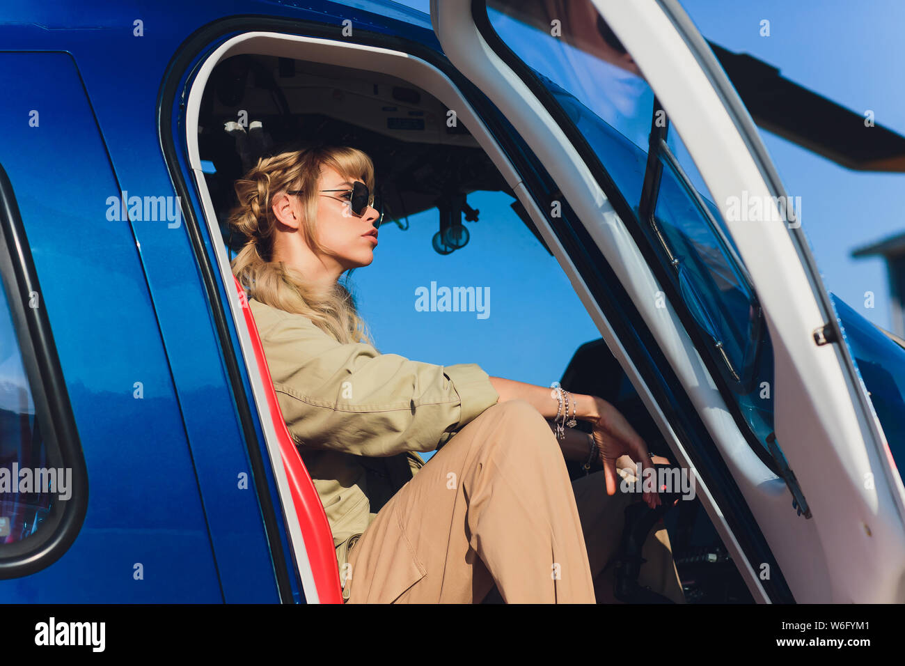 Female pilot in cockpit of helicopter before take off. Young woman ...