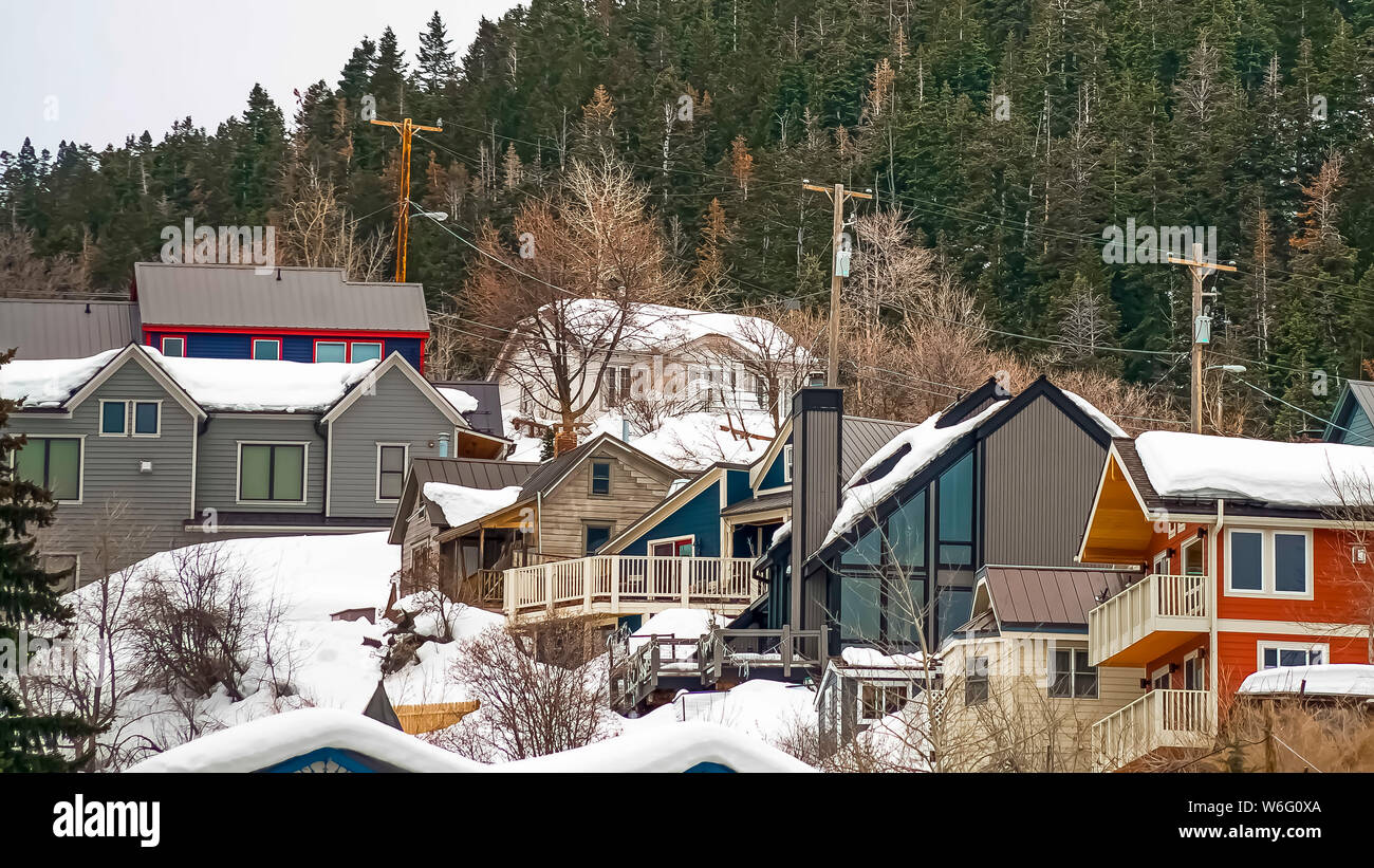 Panorama frame Mountain homes with snow covered roofs aginst coniferous ...