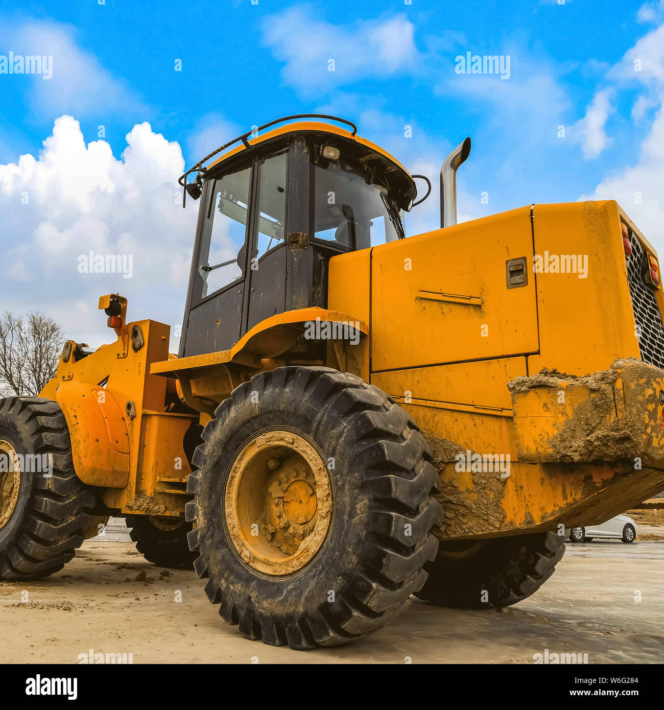 frame Close up of a dirty yellow loader with black rubber wheels and ...