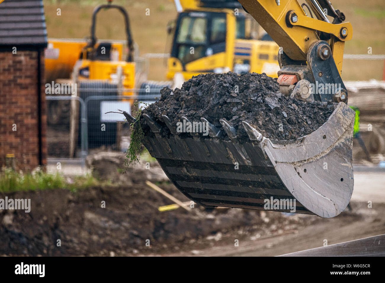 A digger and dump truck move dirt to make room for the foundations ...
