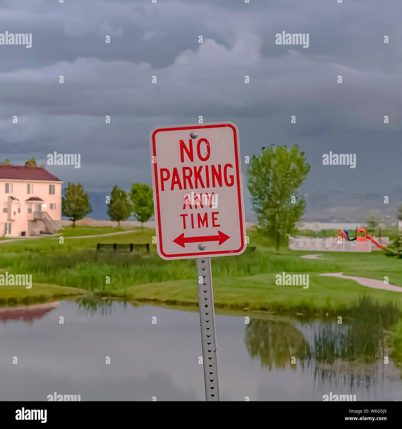 Square frame No Parking At Any Time sign with pond grassy terrain and ...