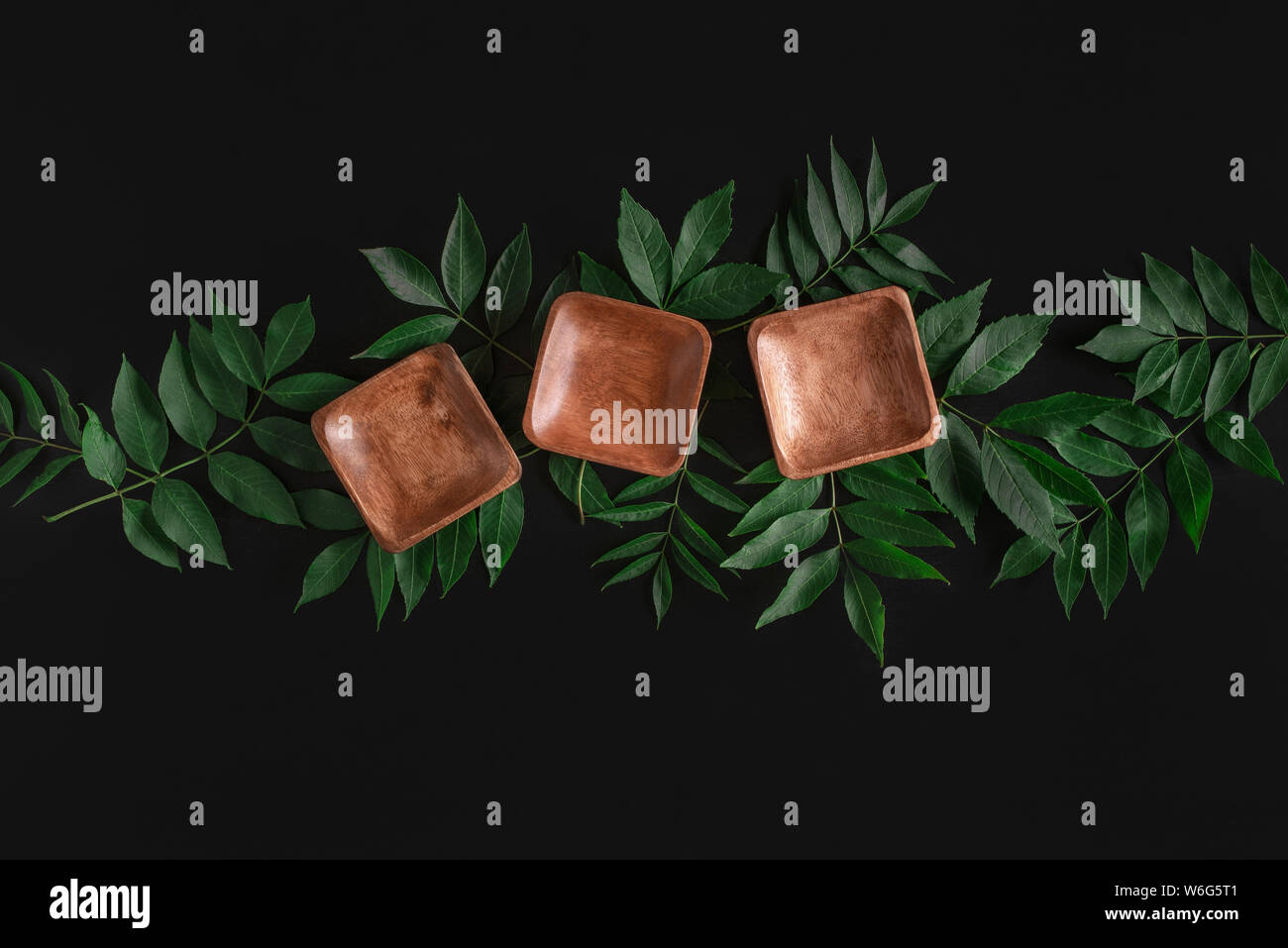 Food background with organic wooden bamboo plates on green leaves, on a ...