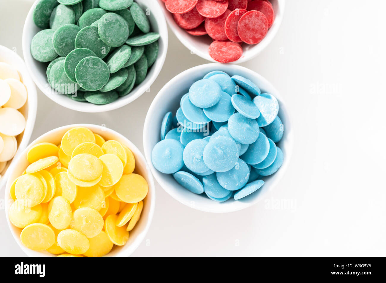 Rainbow colors of round chocolate chips in a white bowls for melting ...