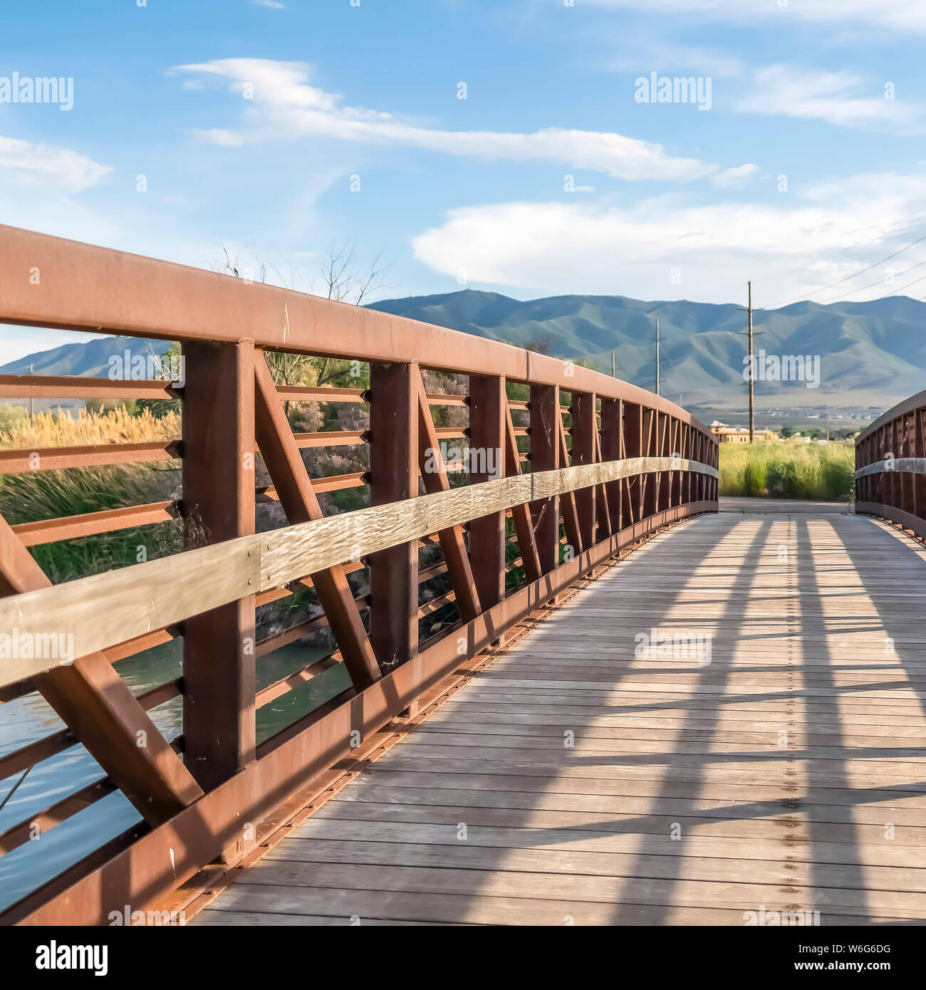 Square frame Wooden bridge with metal lattice guardrail over a lake ...